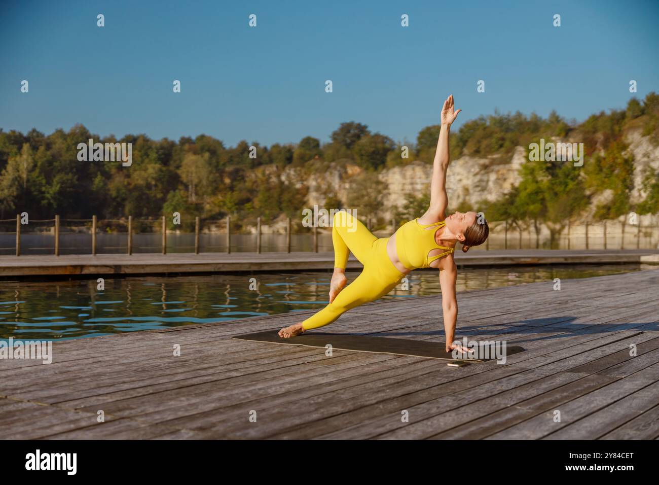 A dynamic yoga pose by the water in vibrant attire, blending energy and ...