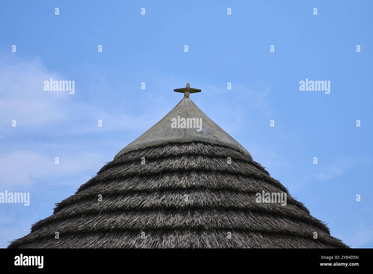 Traditional thatched roof in front of a clear blue sky with light ...