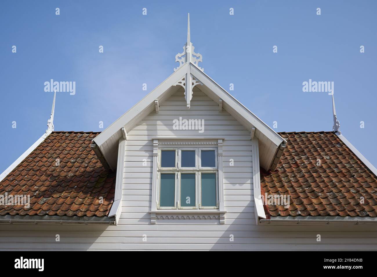 A traditional house with a red tiled roof and white wooden gable under ...