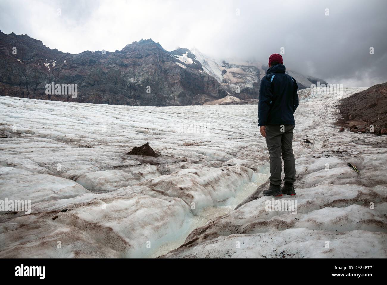 Eroded Elegance of mount Kazbegi: A trekker stands on a snowy slope ...