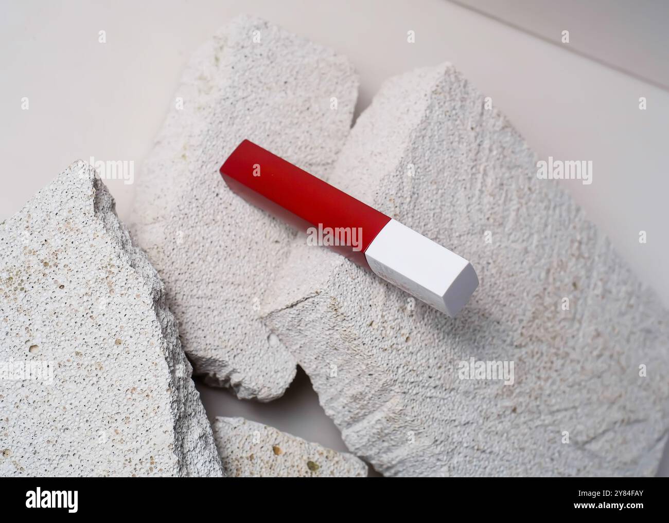 A striking red lipstick tube elegantly displayed against a textured ...