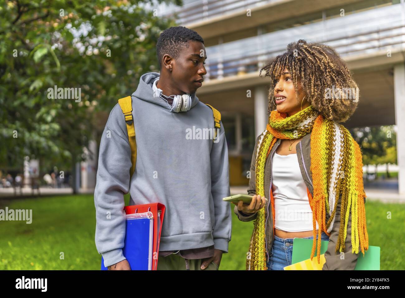 Two young and multiracial students chatting in the university campus ...