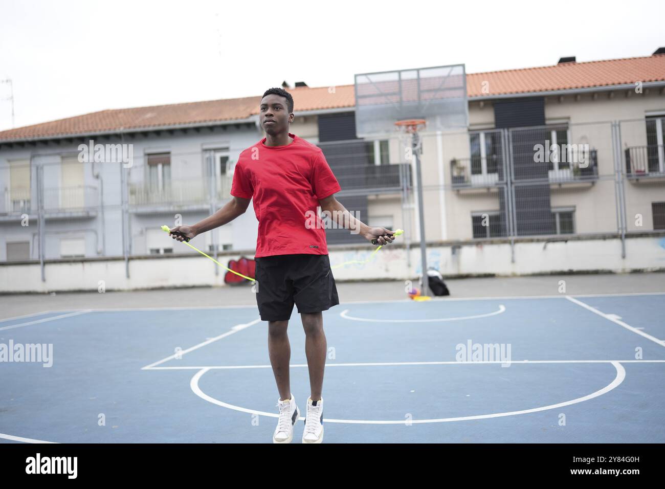 Horizontal full length photo of an african young sportsman jumping rope ...
