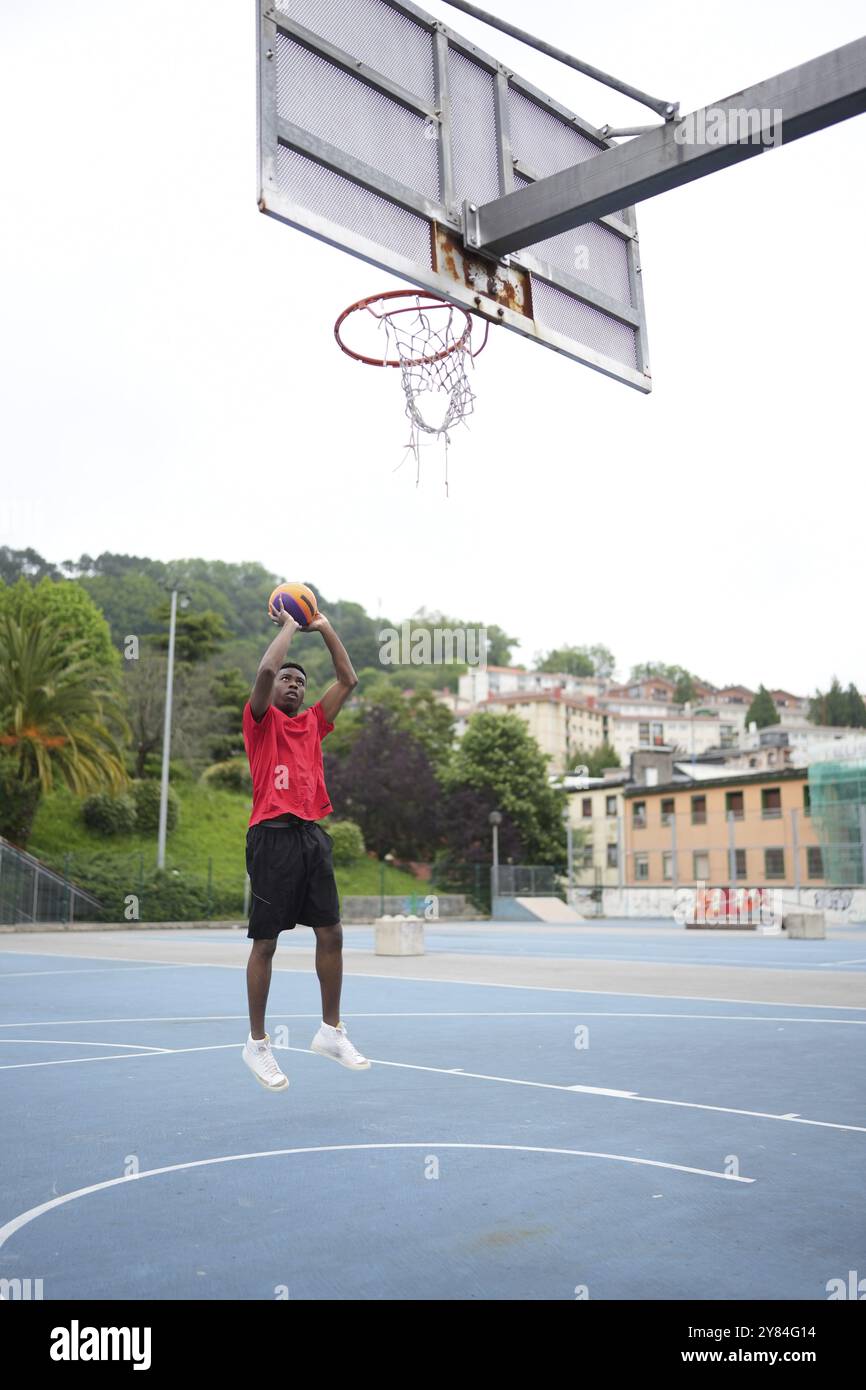 Vertical photo of a basketball player throwing a ball in an outdoor ...