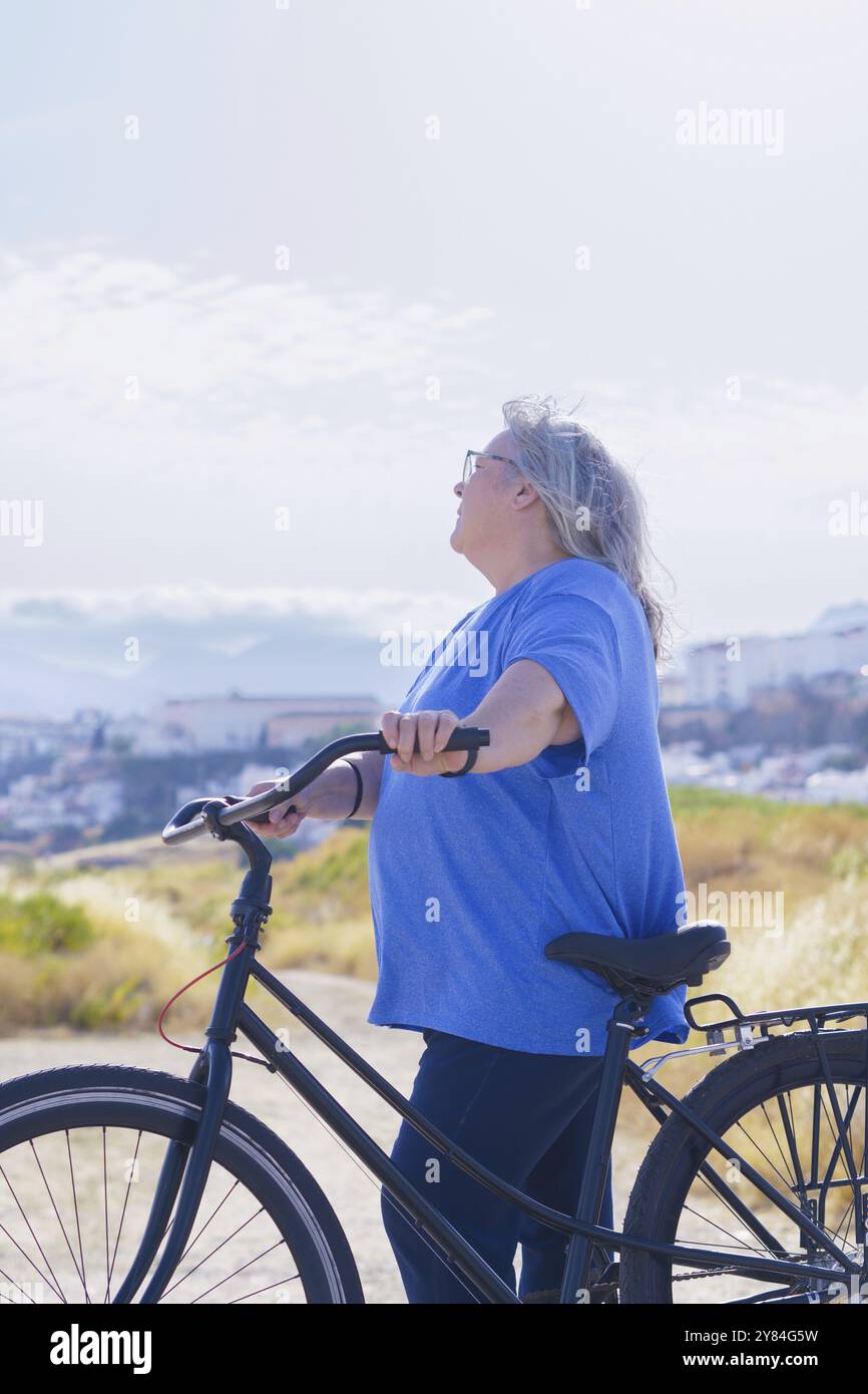 An overweight mature woman rides a black retro-style bicycle against a ...