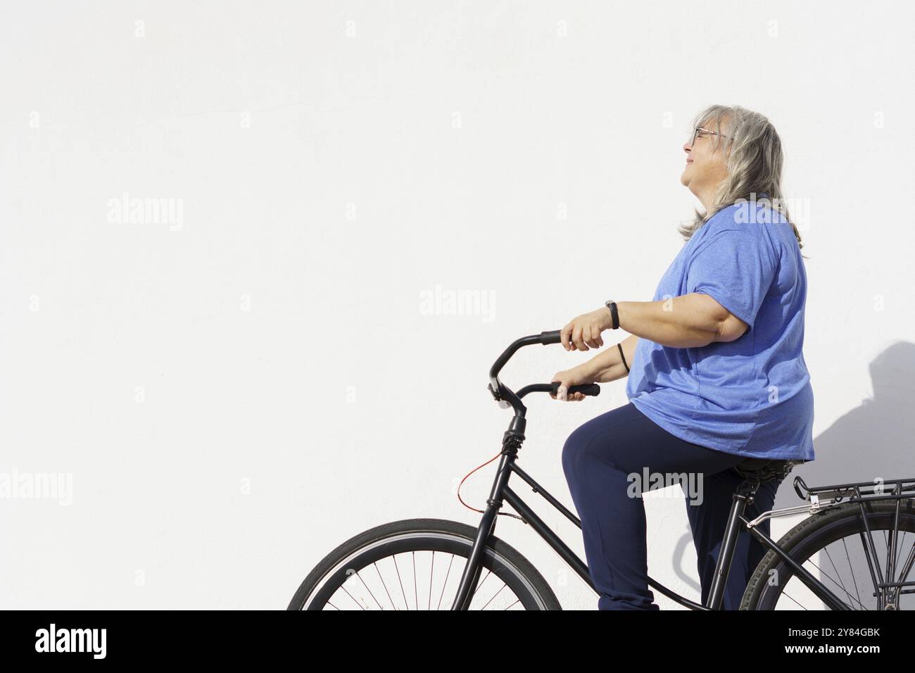 Smiling overweight mature woman riding a retro style bicycle isolated ...