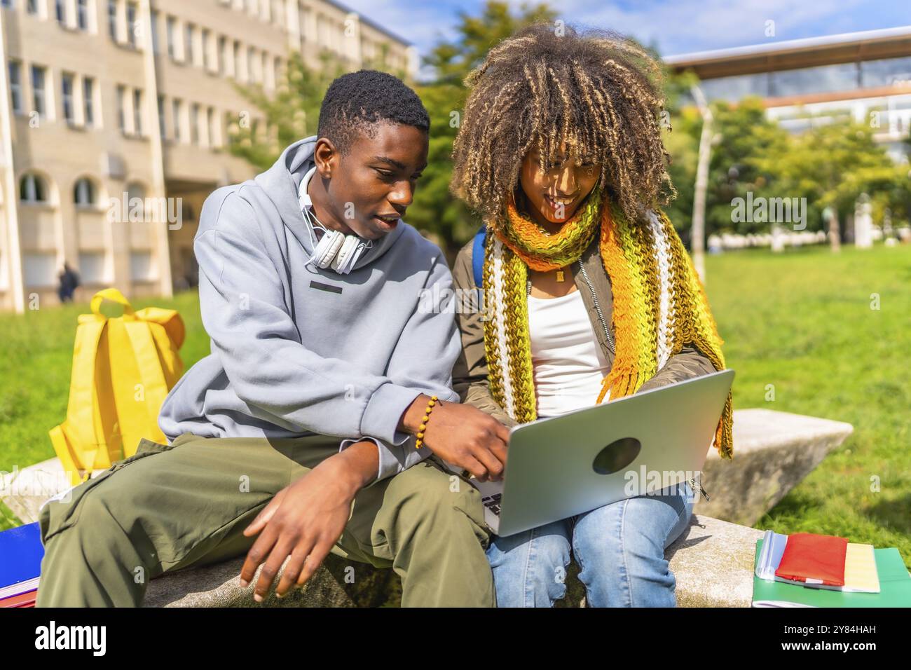 Multi-ethnic students using laptop sitting outside the university ...