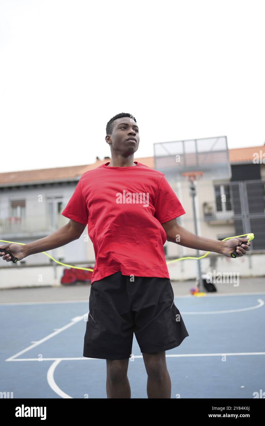 Vertical photo of a sportive afro young man skipping rope in a ...