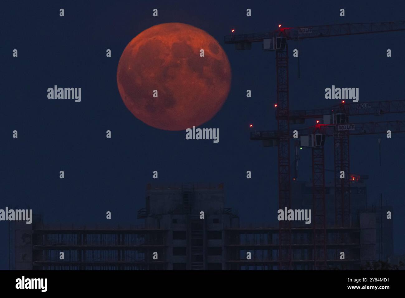 The full moon passes over a construction site in Offenbach am Main. A ...