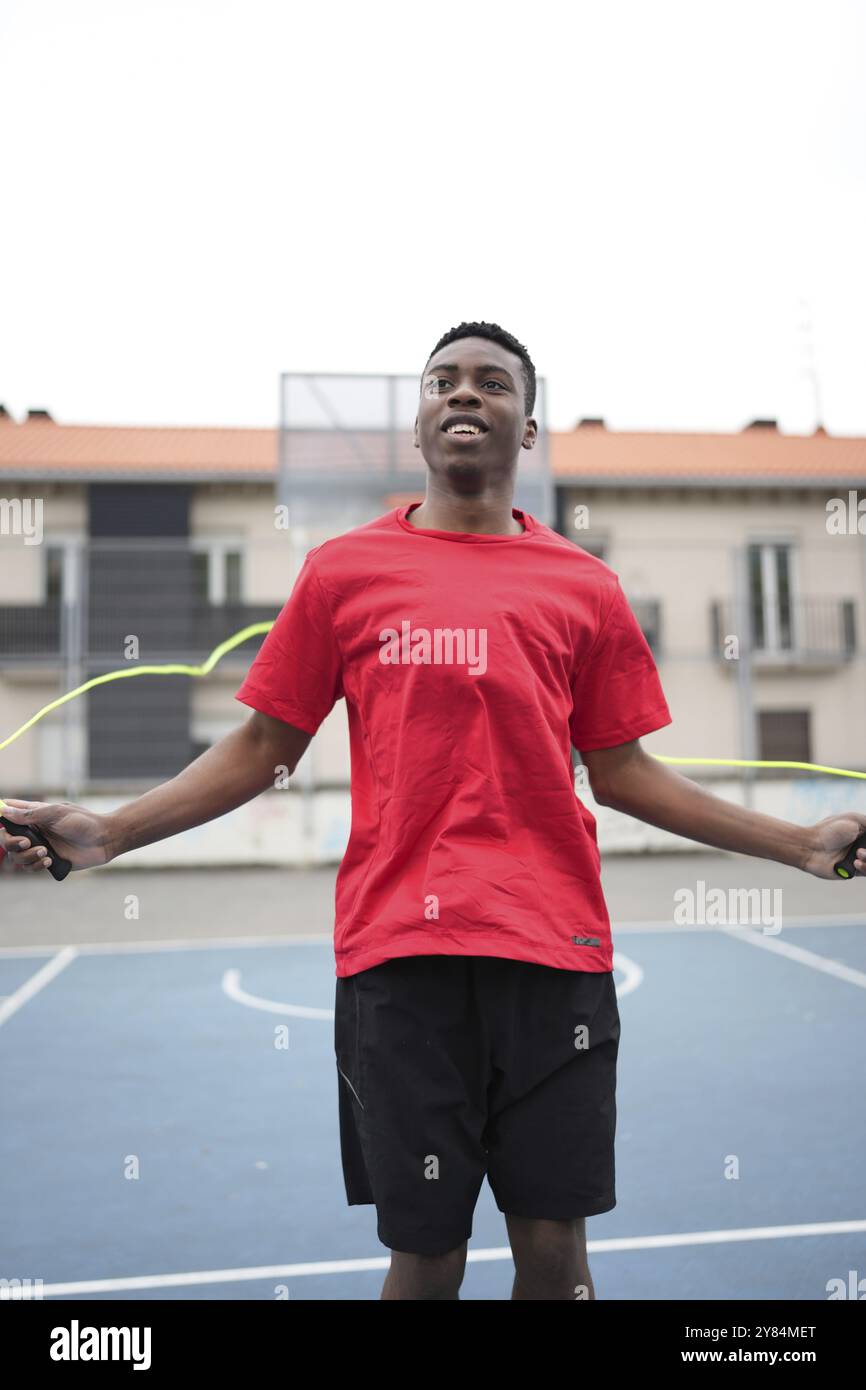 Vertical photo of an african young man jumping rope in an urban outdoor ...