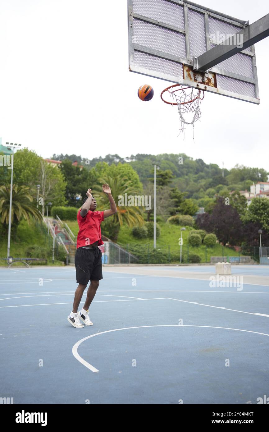 African sportive man scoring throwing a ball in an outdoor court Stock ...