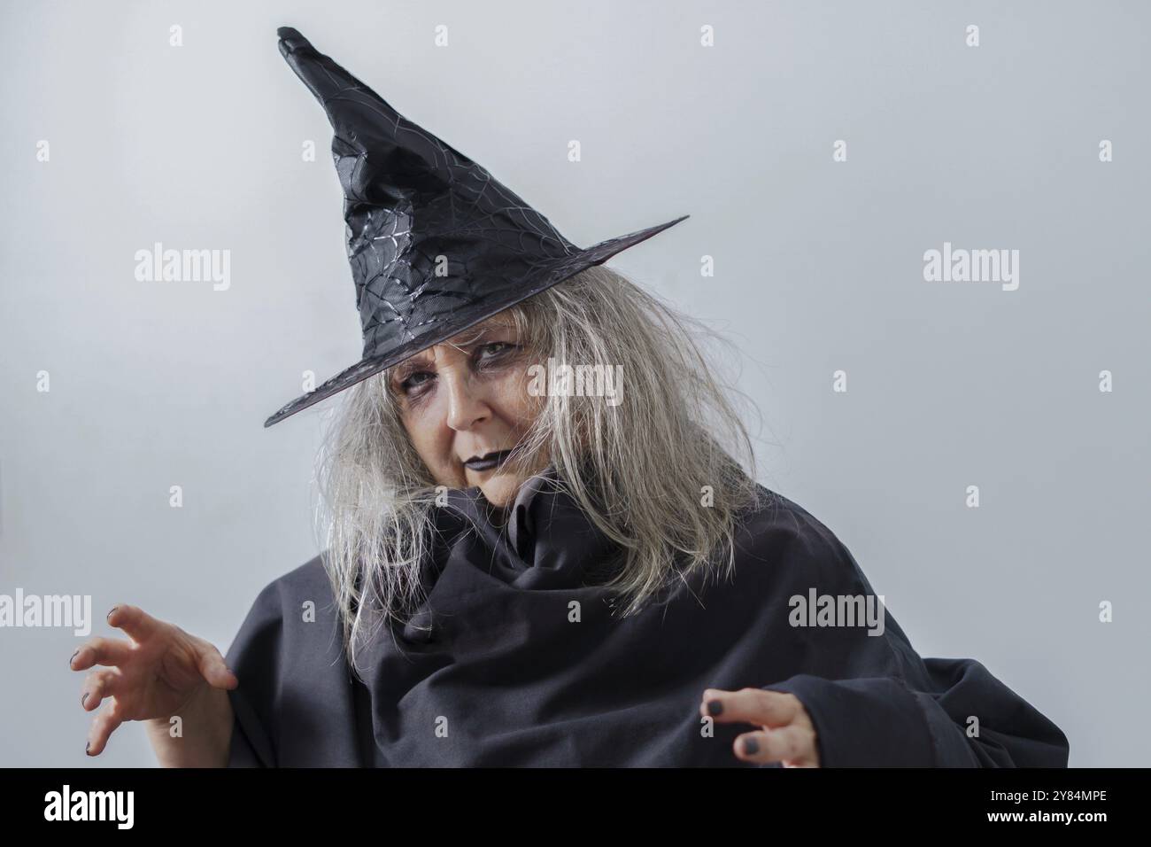 Old white-haired white-haired witch dressed in black with hat on light background Stock Photo ...