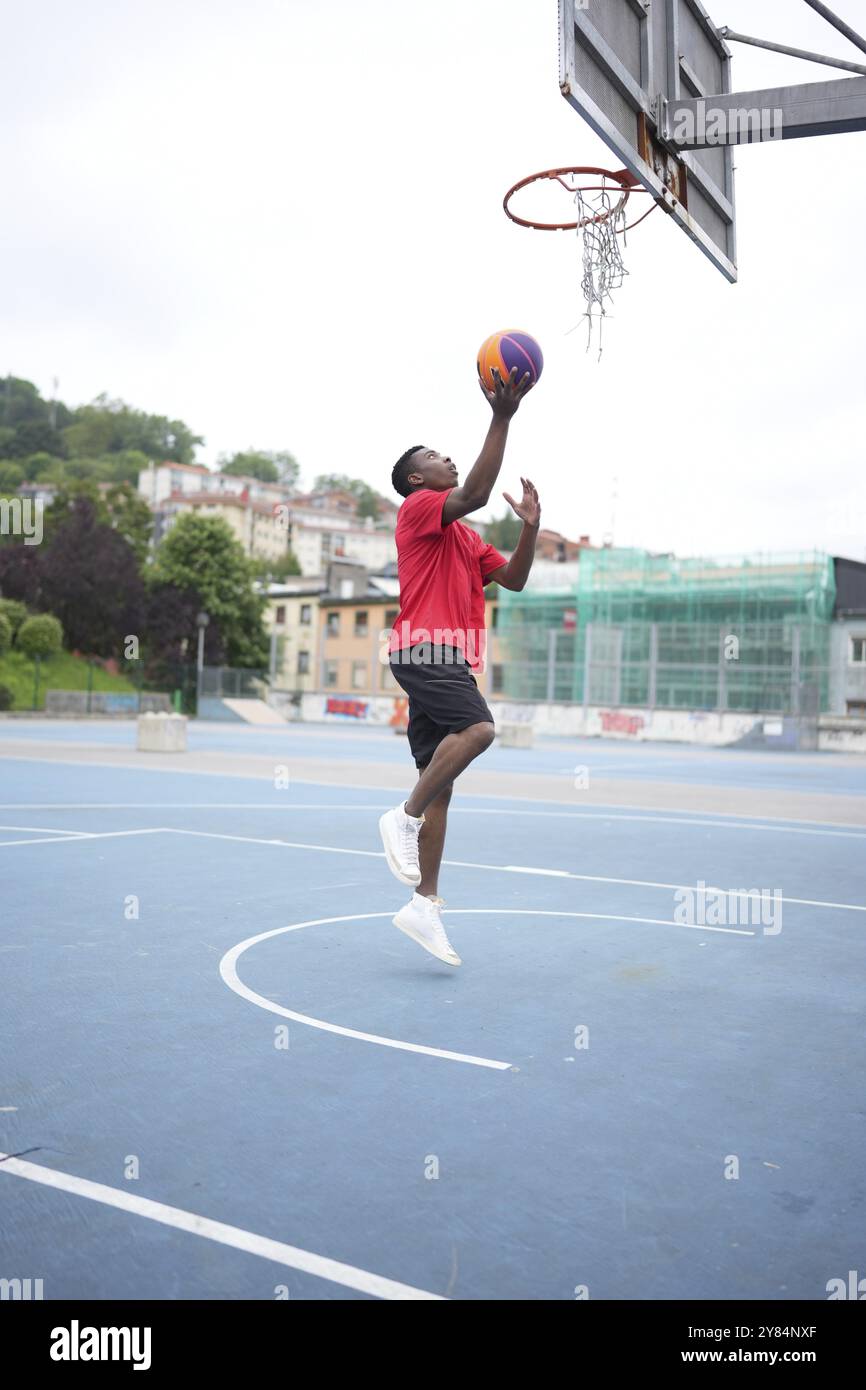 Vertical photo of a ypung african male basketball player jumping to ...