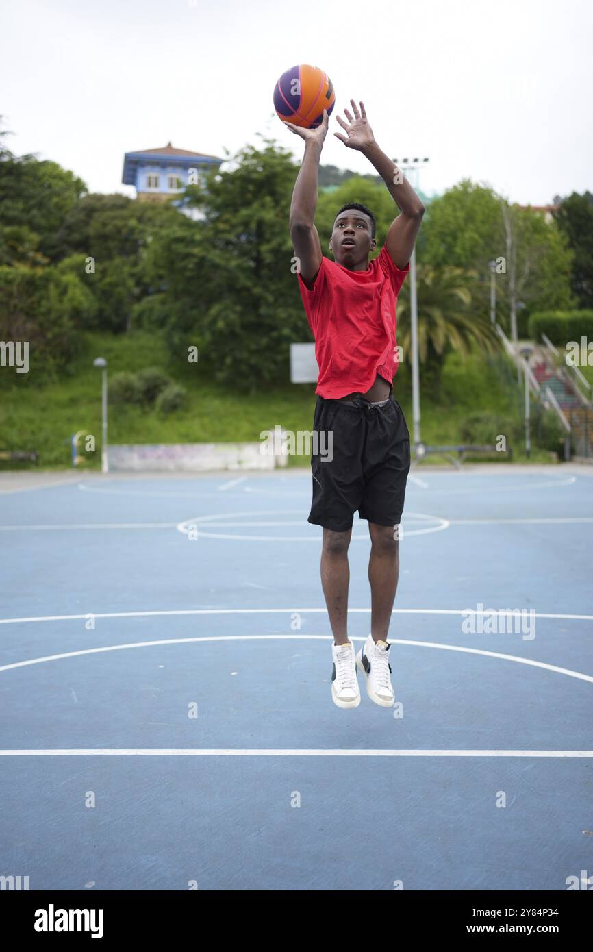 Vertical photo of an african basketball player man throwing the ball in ...