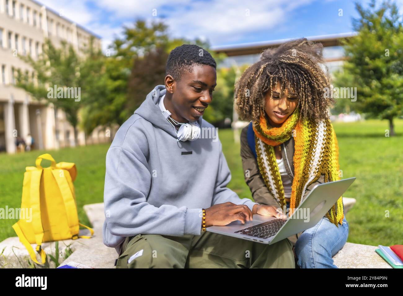 Two multi-ethnic students using laptop sitting outside the campus Stock ...