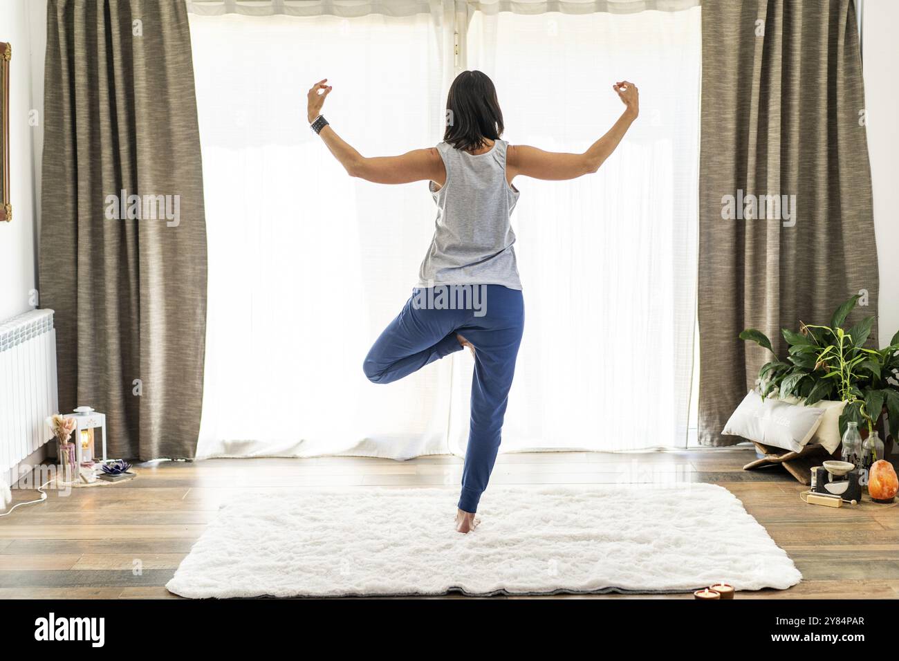 Rear view of a dedicated woman engaging in yoga and performing mudras ...