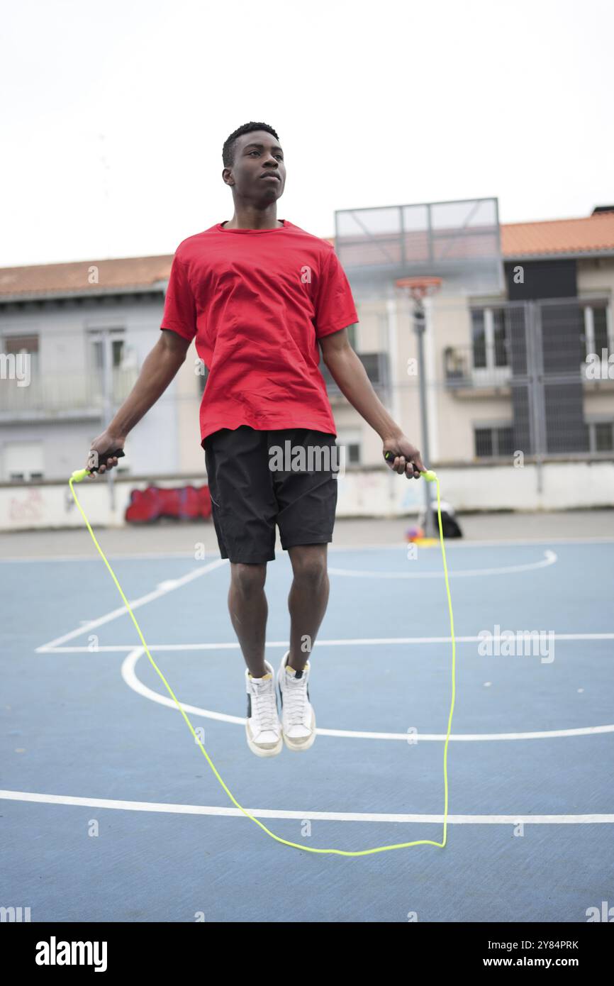 Vertical photo of a sportive african young basketball player skipping ...