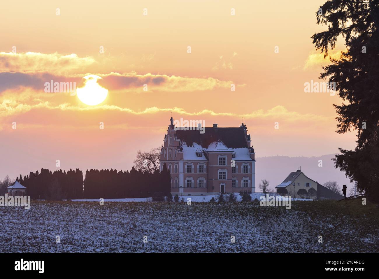 A castle at sunset in a snowy winter landscape, surrounded by trees ...