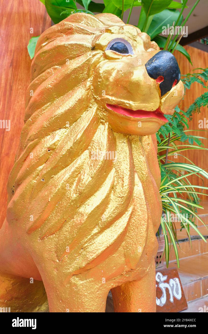 A fancy, gold, regal, smiling lion figure statue. At Wat Si Muang ...
