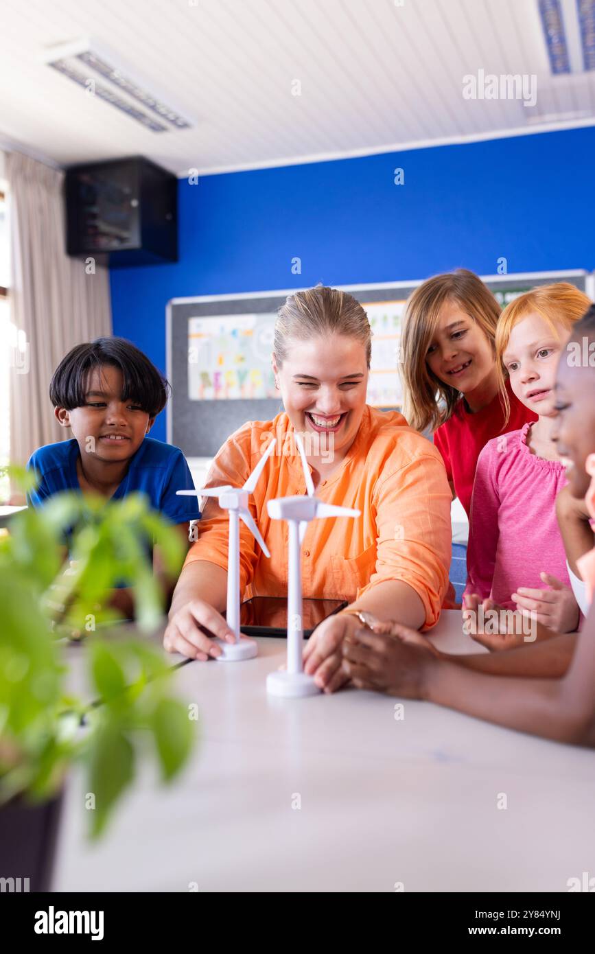 In school, female teacher and diverse students experimenting with wind ...