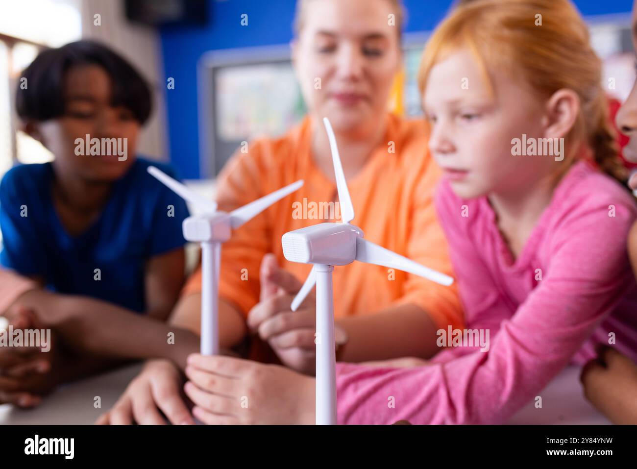 In school, diverse children learning about wind turbines with female ...