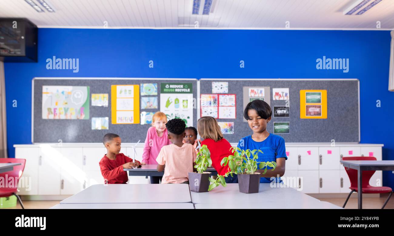 In school, diverse children working together on plant project in ...