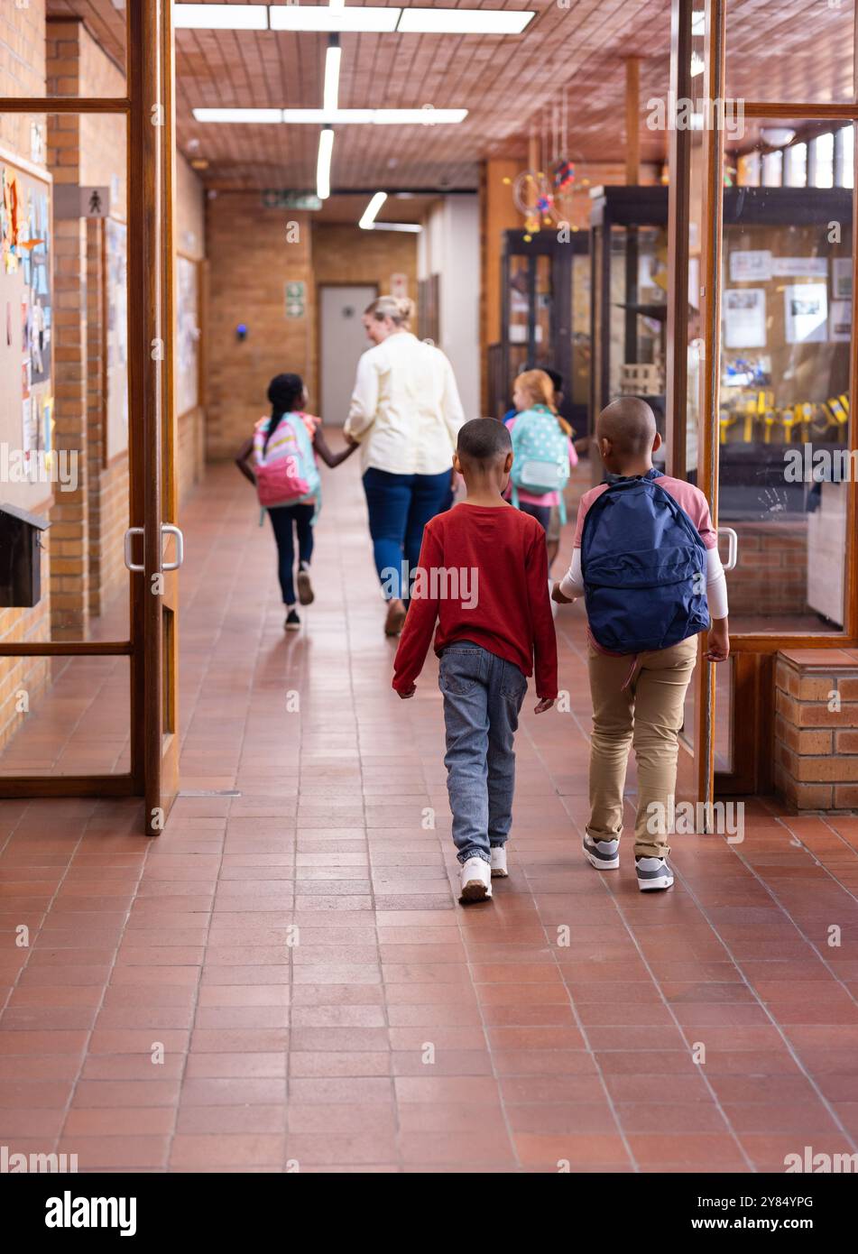 Walking in school hallway, diverse children with backpacks heading to ...
