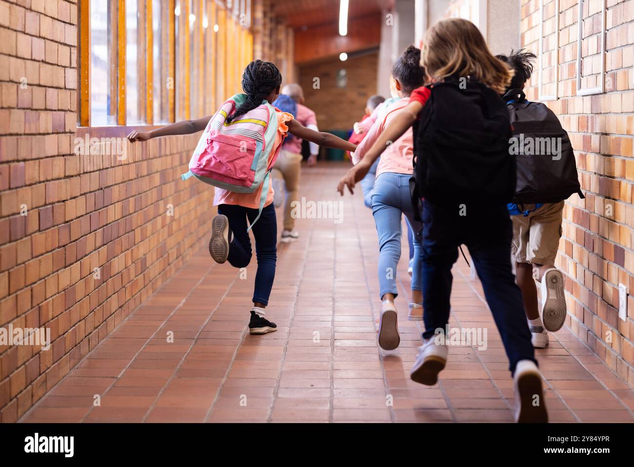 Running in school hallway, group of diverse children with backpacks ...