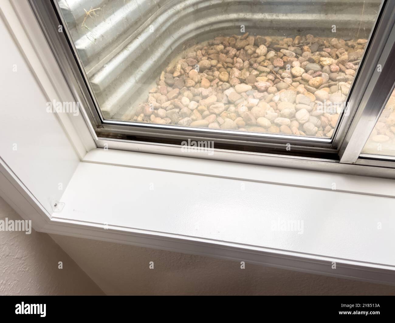 Basement Window with Metal Window Well and Rocks Stock Photo - Alamy