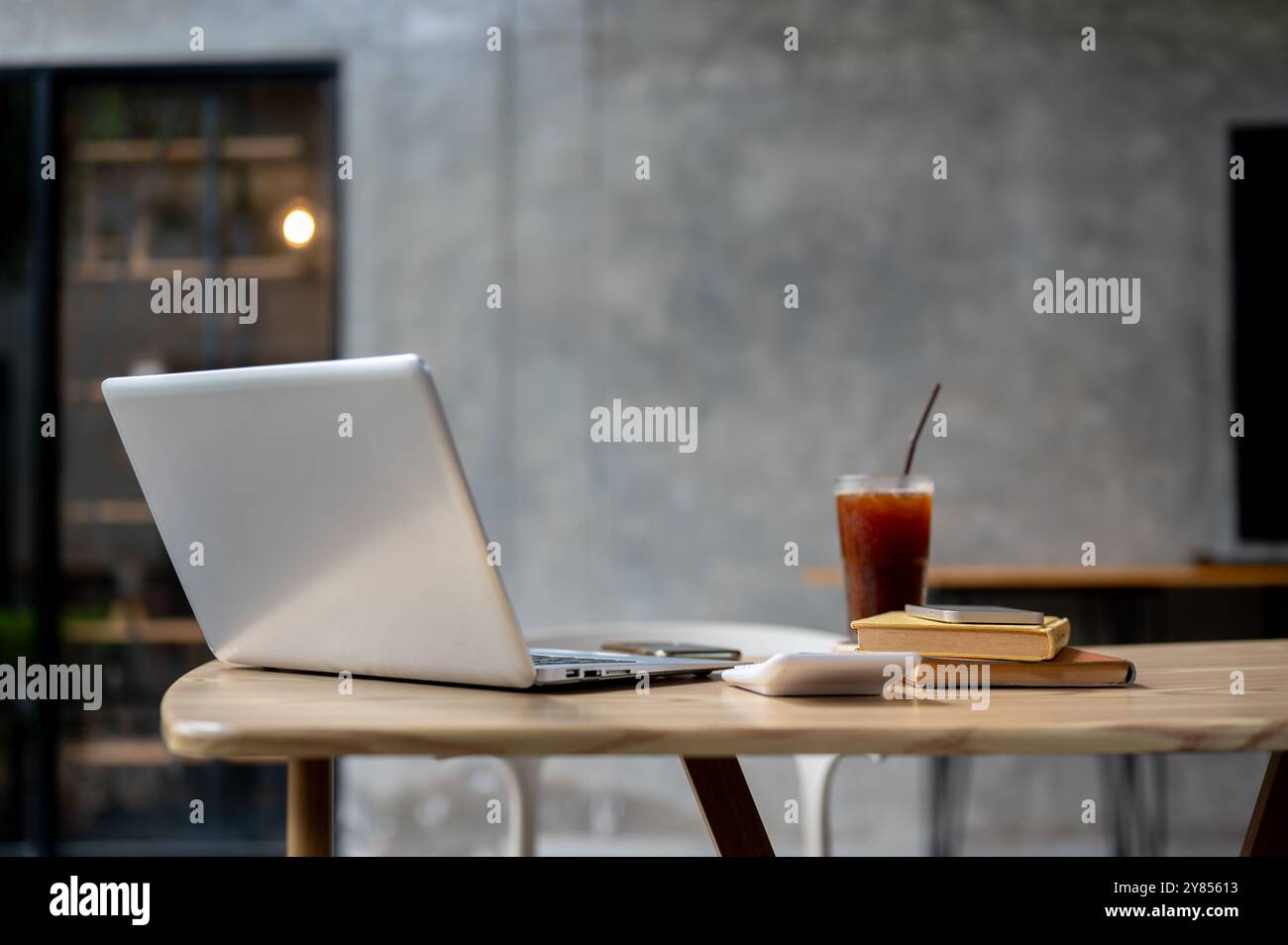 A close-up of a laptop, a calculator, books, and a glass of iced coffee ...