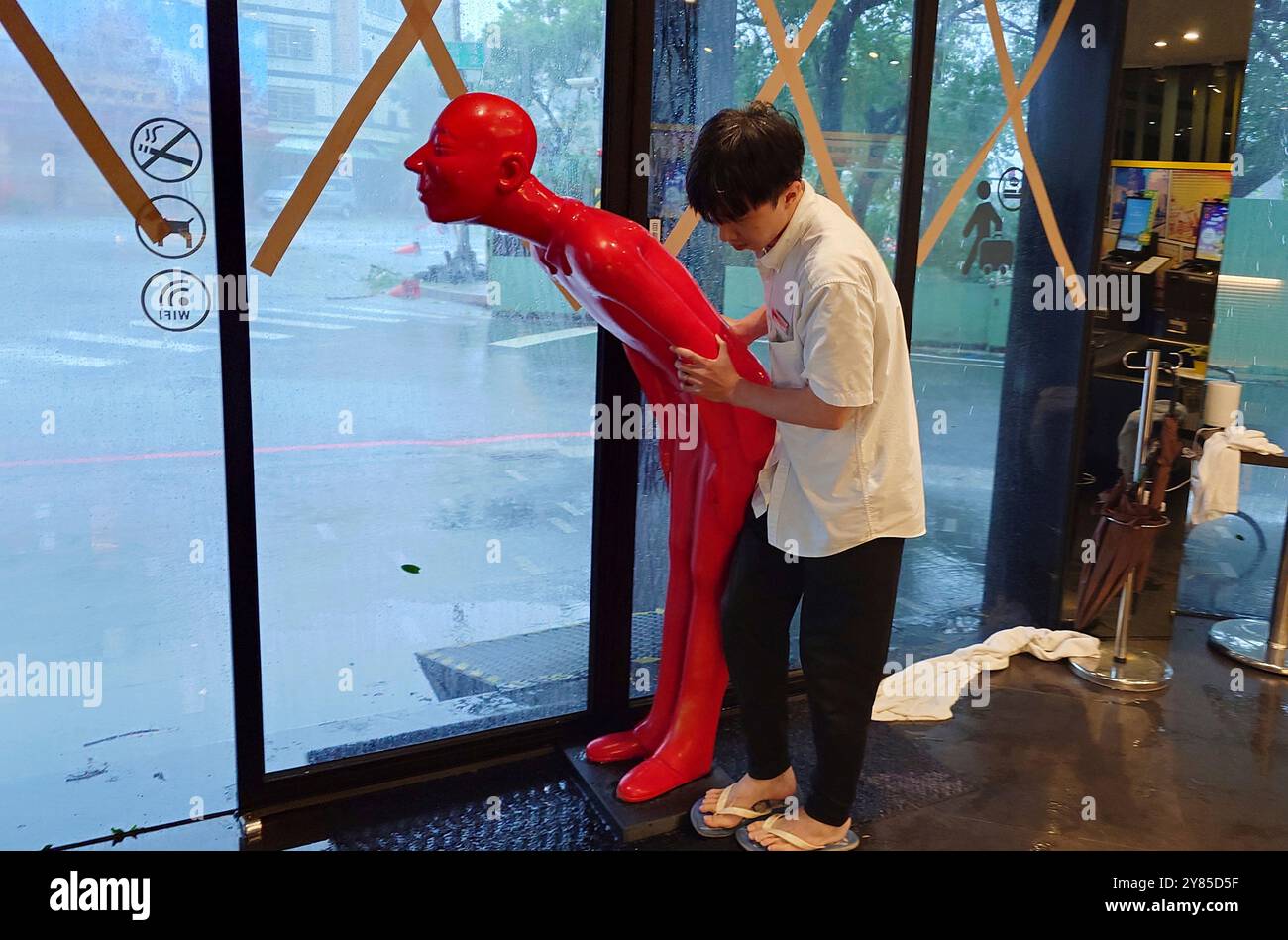 A hotel staff prepares to move a human figure from the doorway to ...
