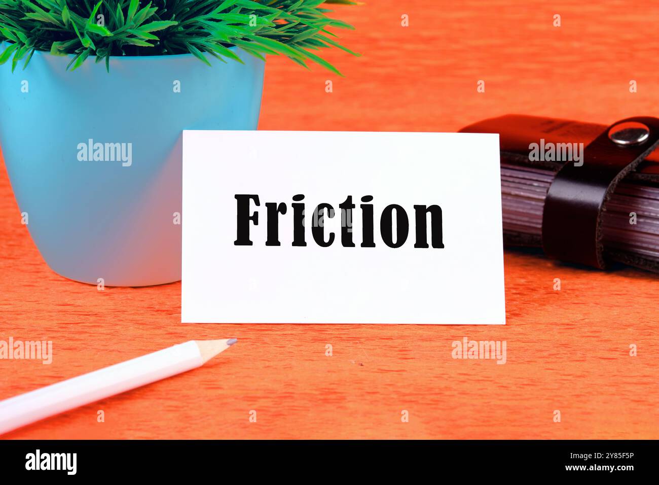 Friction concept. Friction word on a white business card on an orange ...