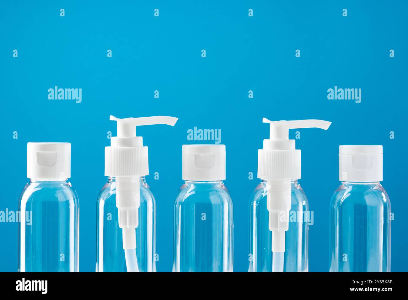 Clear plastic bottles with pumps arranged on a table against a bright ...