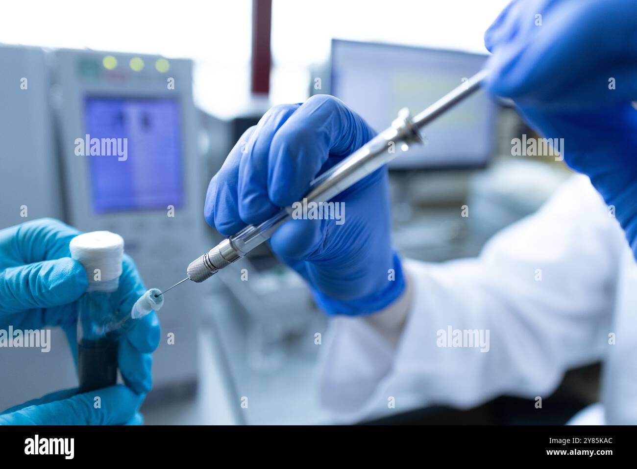 Scientist injecting a sample via the autosampler of HPLC system. High ...