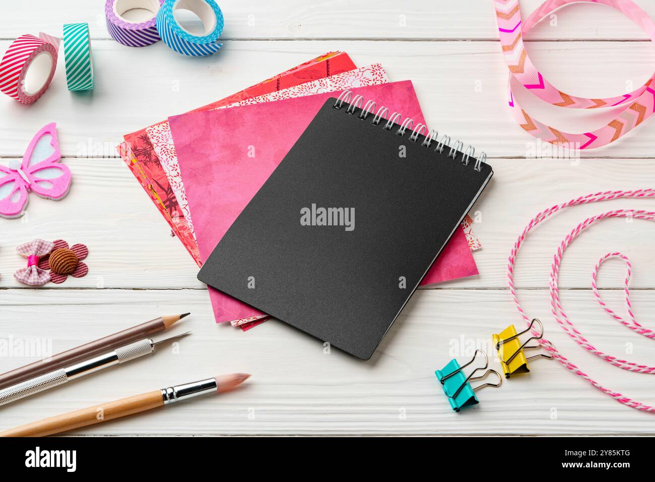 Crafting essentials on a workspace featuring a black notebook, colorful ...