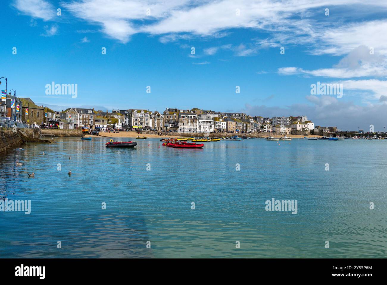Flat calm water and boats in St Ives Harbour at high tide on a sunny ...