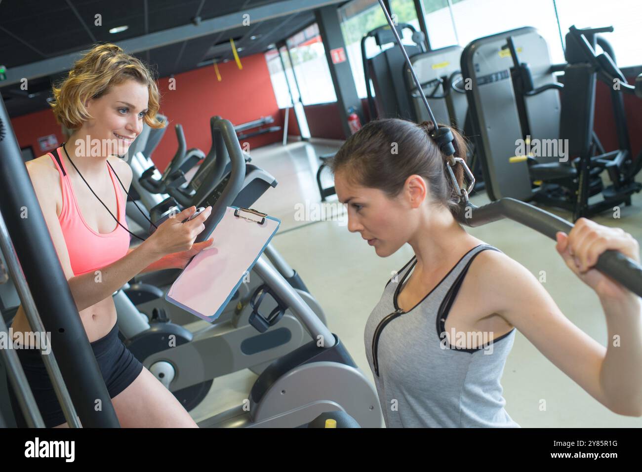 coach with customer using an exercise machine Stock Photo - Alamy