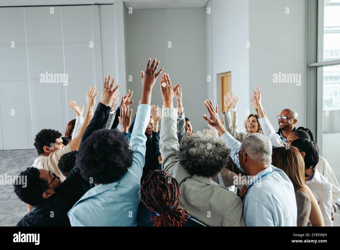 A multiethnic group of colleagues raising their hands in a group high ...