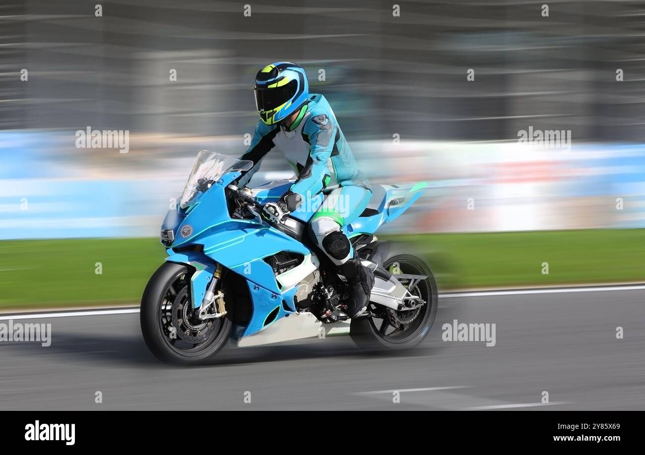 Motorcycle rider in a blue helmet and gear racing at high speed on race ...