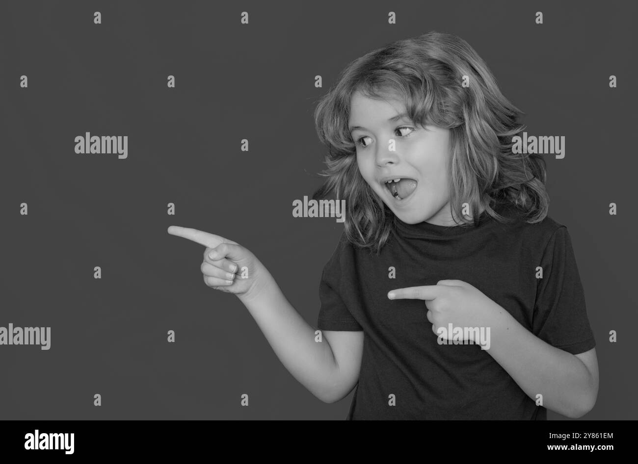 Excited kid boy on studio isolated background. Kid pointing finger away ...