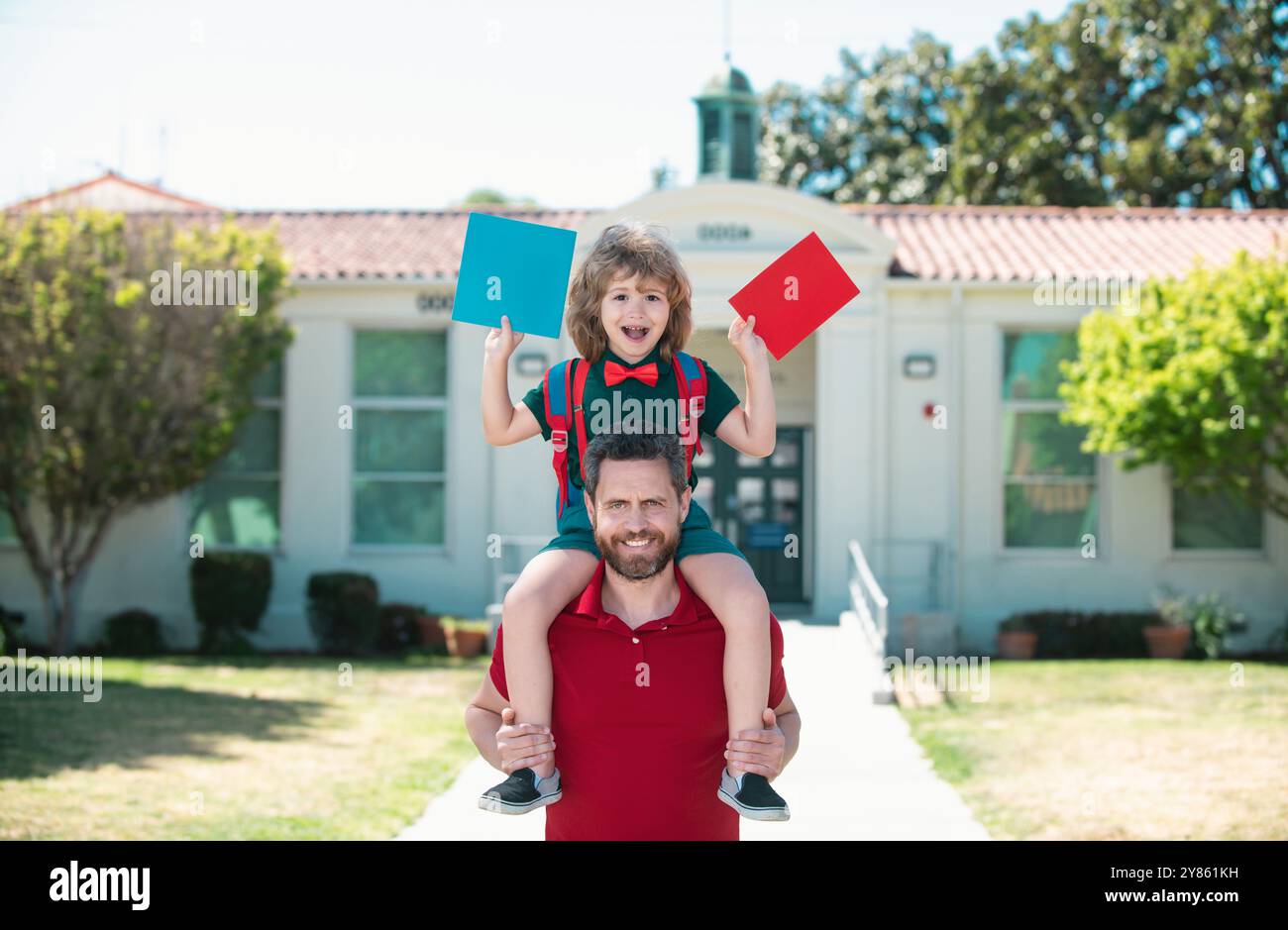 Father and son walking trough school park. Man giving son piggyback ...