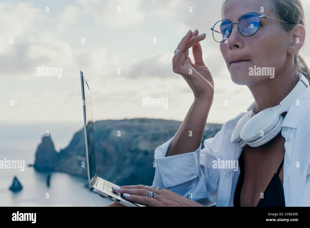Woman Laptop Beach Work Remotely - A woman in a white shirt works on a ...