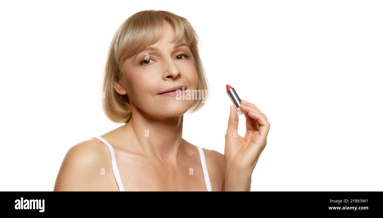 Mature woman holds lipstick confidently, ready to apply it, showing ...
