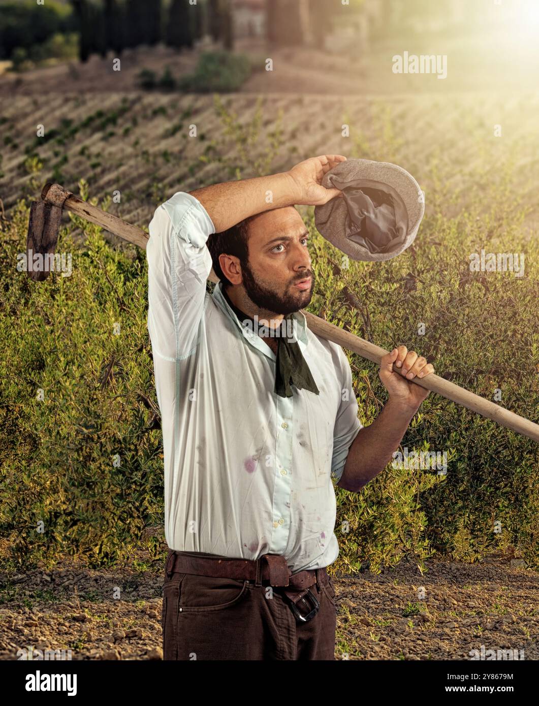 Tired farmer wiping sweat from his brow with his hat in hand while ...