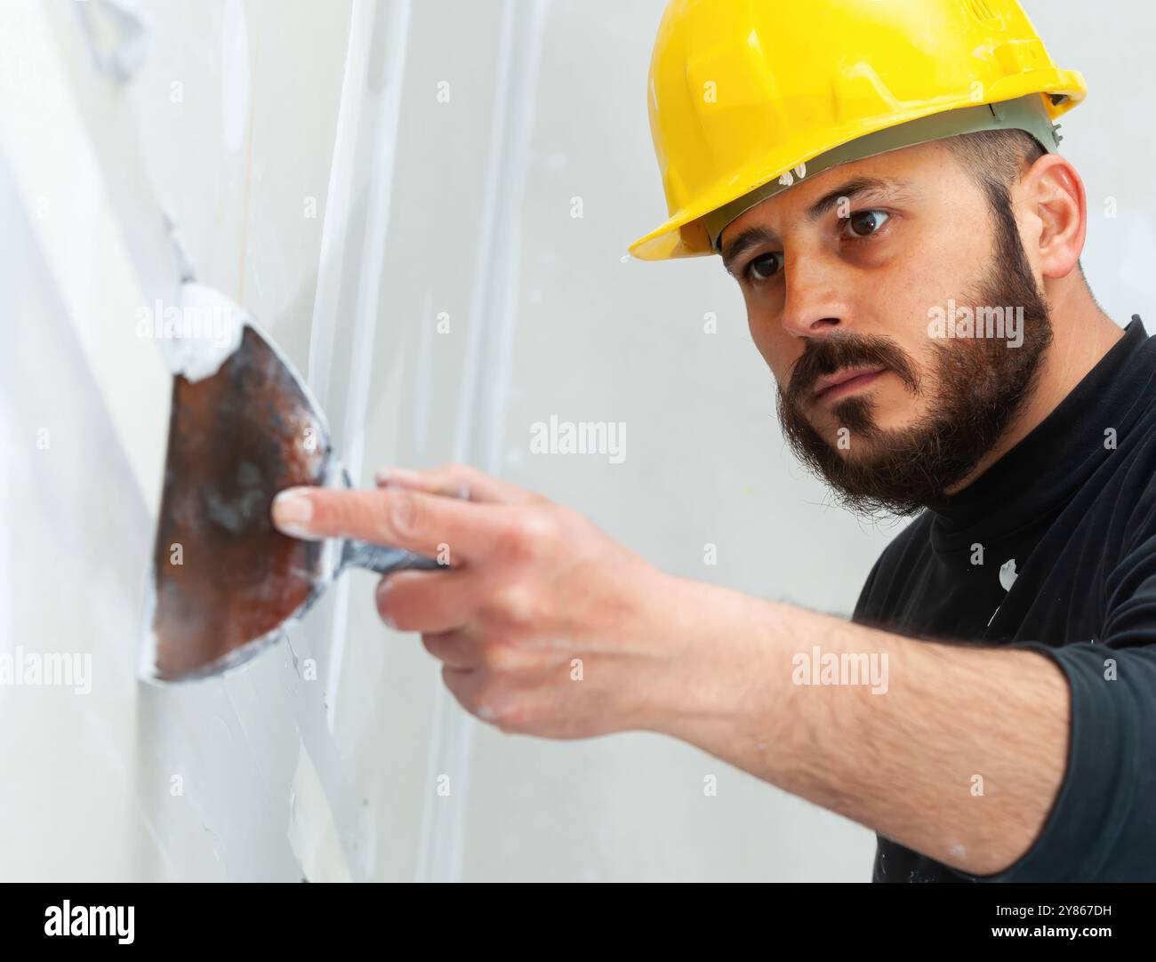 Construction worker wearing a safety helmet plastering a white wall ...