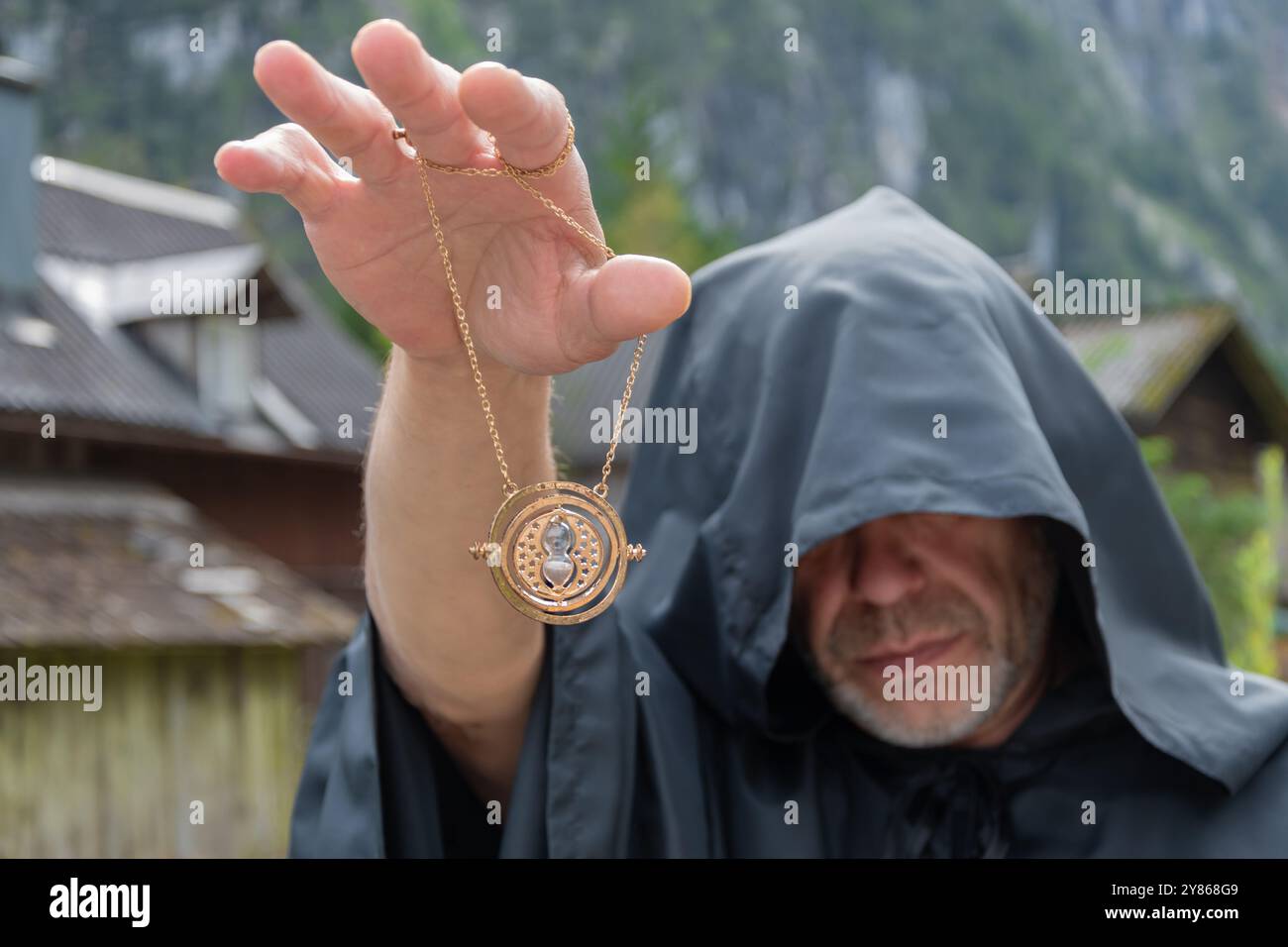 An old monk with a beard holds an hourglass amulet in his hand Stock ...