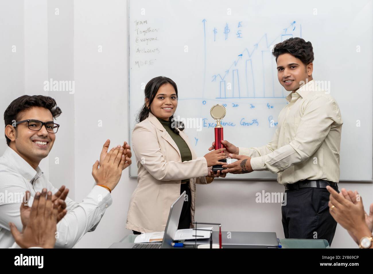 In a corporate office setting, a businessman awards a trophy to the ...