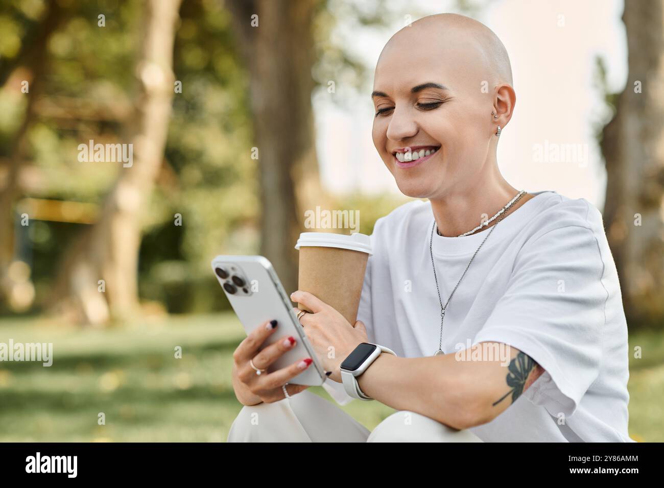 A cheerful bald woman dressed elegantly sips coffee while engaging with ...