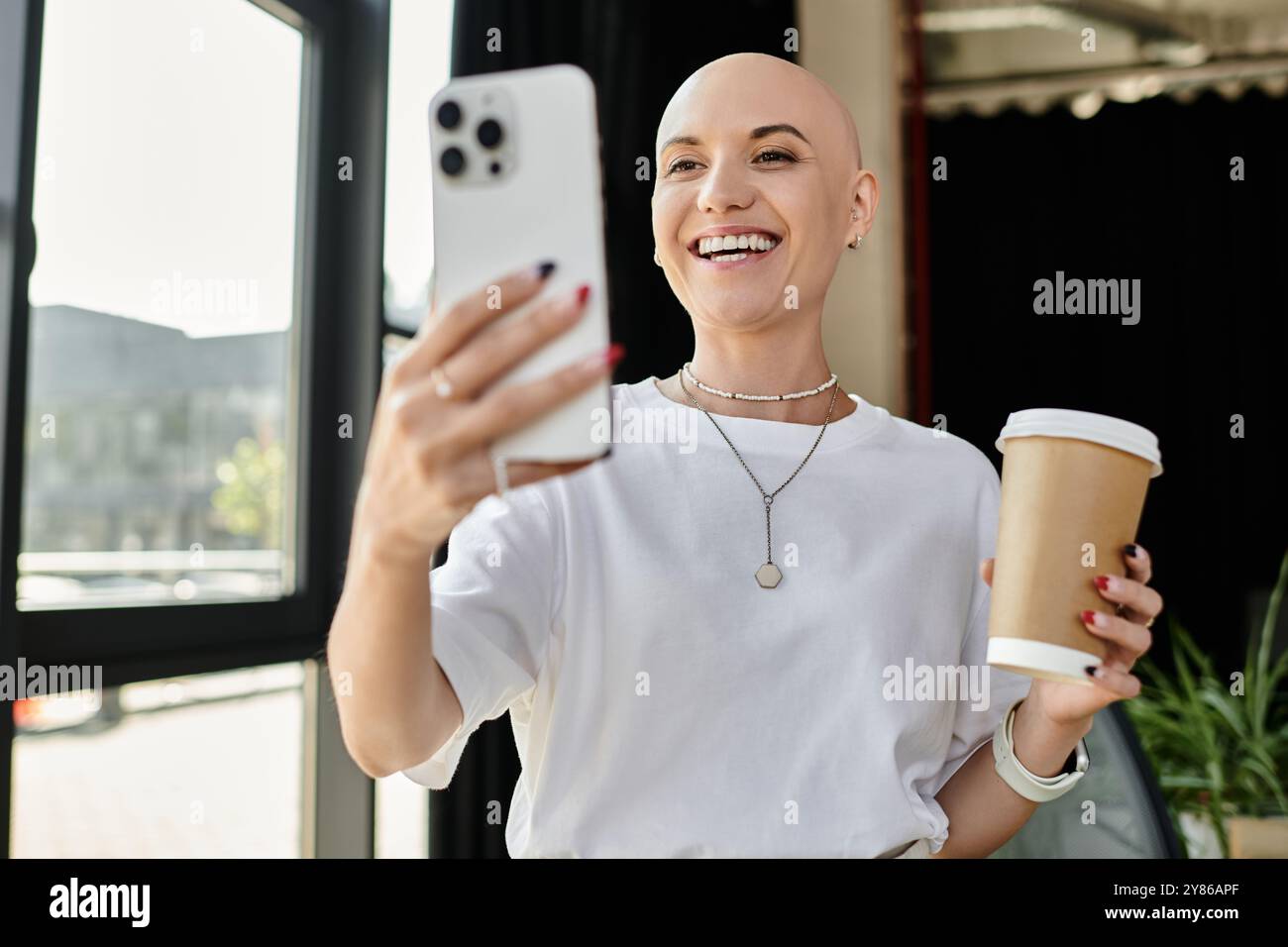 A young bald woman in elegant attire joyfully sips her drink and enjoys ...