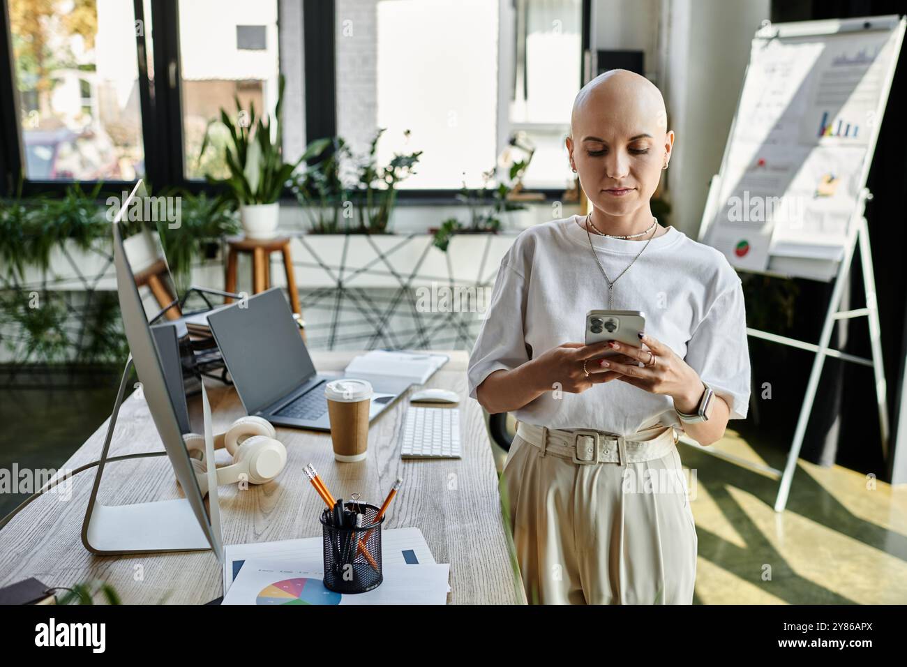 A young bald woman dressed elegantly stands in a chic office, focused ...